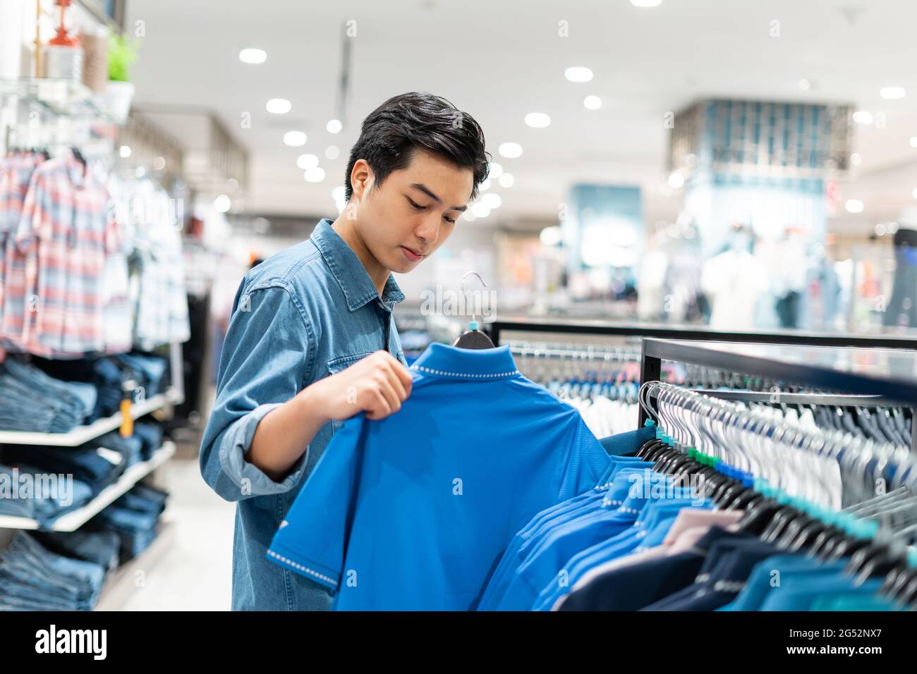 The smart Asian man is choosing clothes in the clothing store in the ...