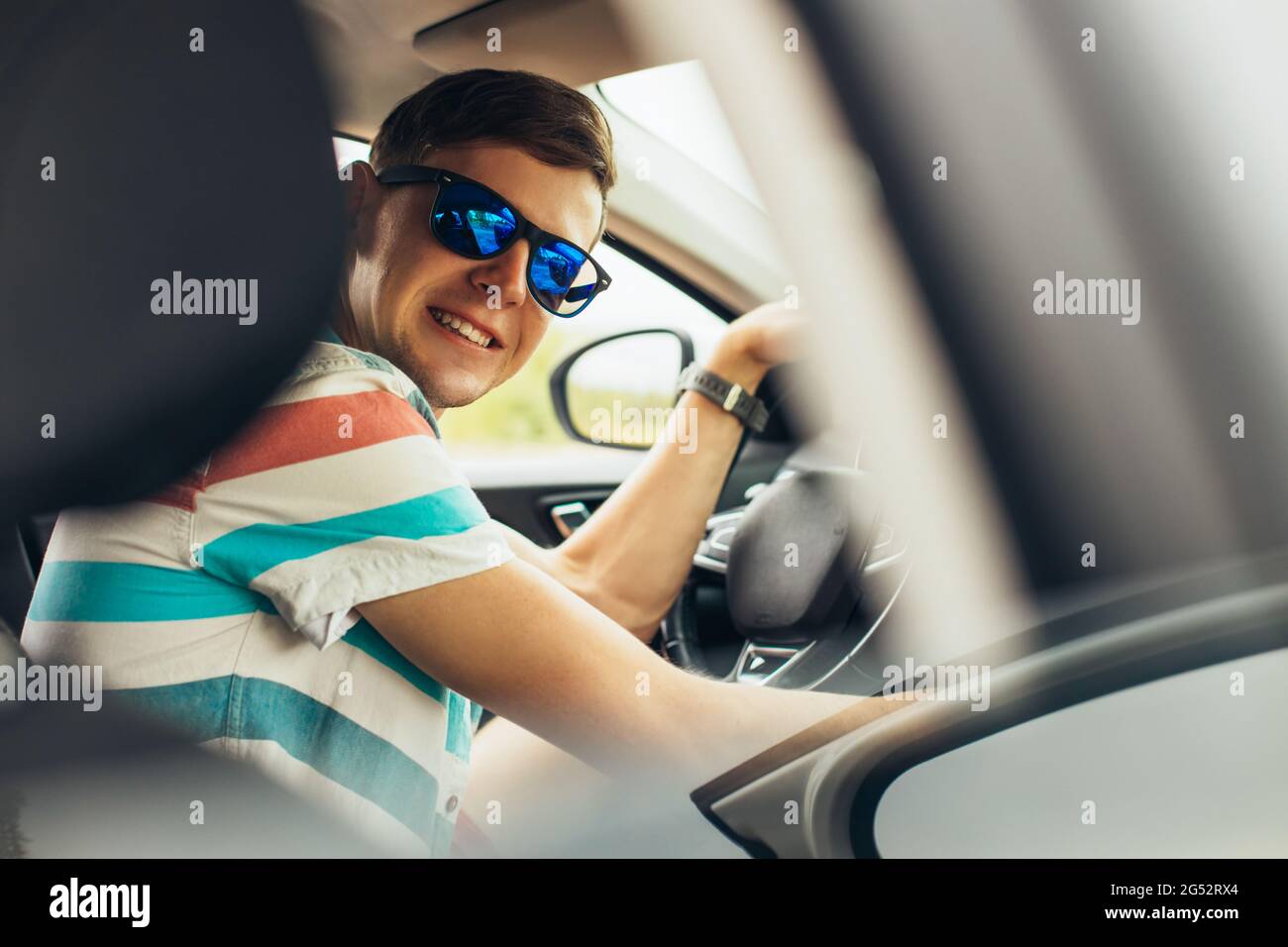 Handsome young man in sunglasses, smiling man driving his new car ...