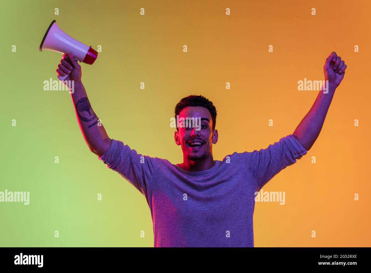 One Latina young man with megaphone, loudspeaker standing hands up ...