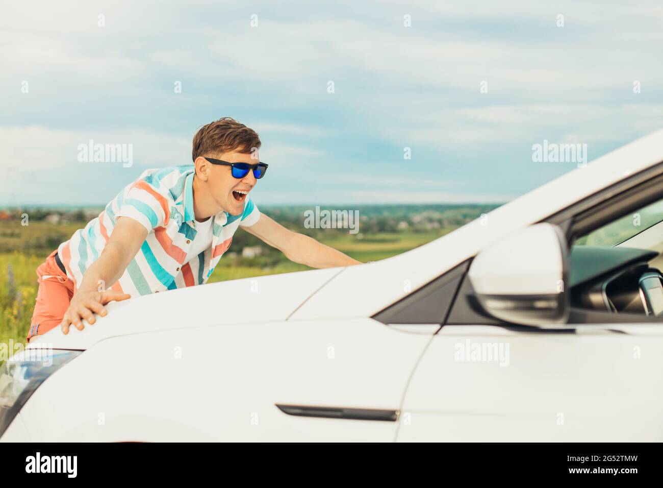Handsome excited young man rejoicing at buying his new car, hugging car ...