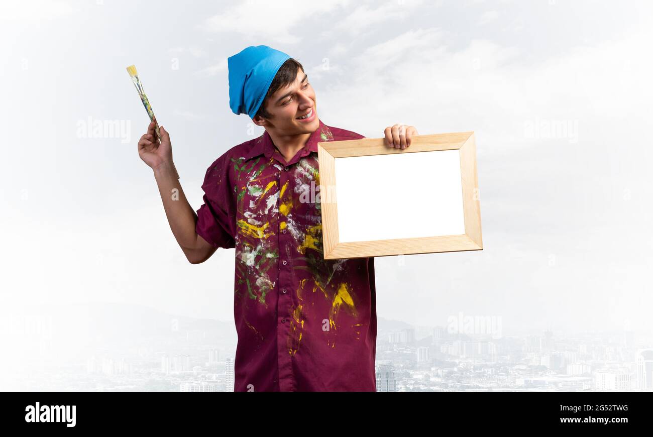 Young handsome painter artist holding paintbrush Stock Photo - Alamy