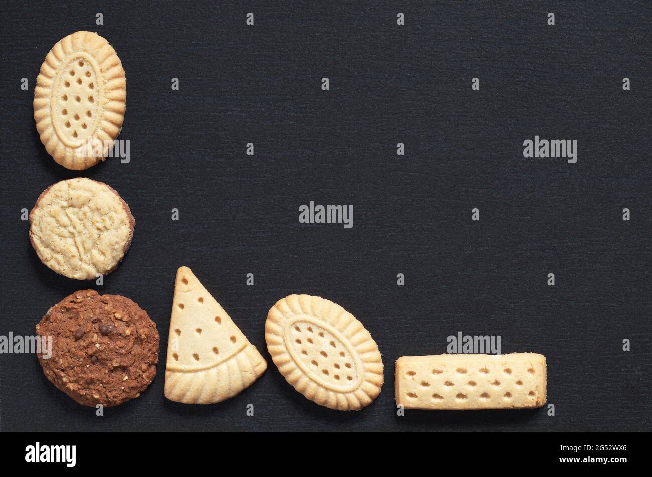 Different shortbread cookies on black stone background, top view. Space ...