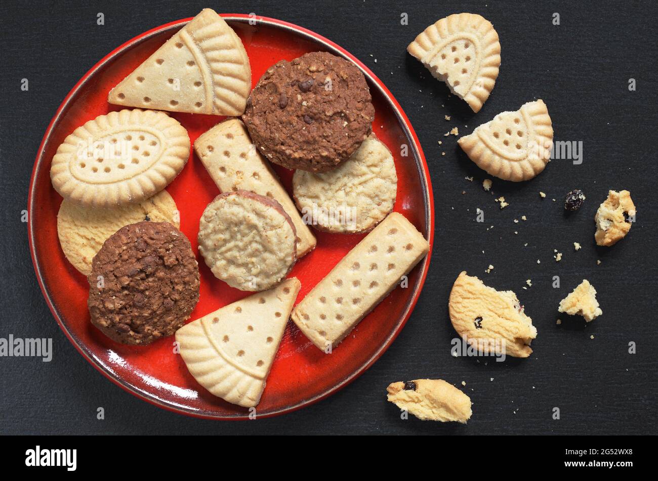 Different shortbread cookies in red plate on black stone background ...