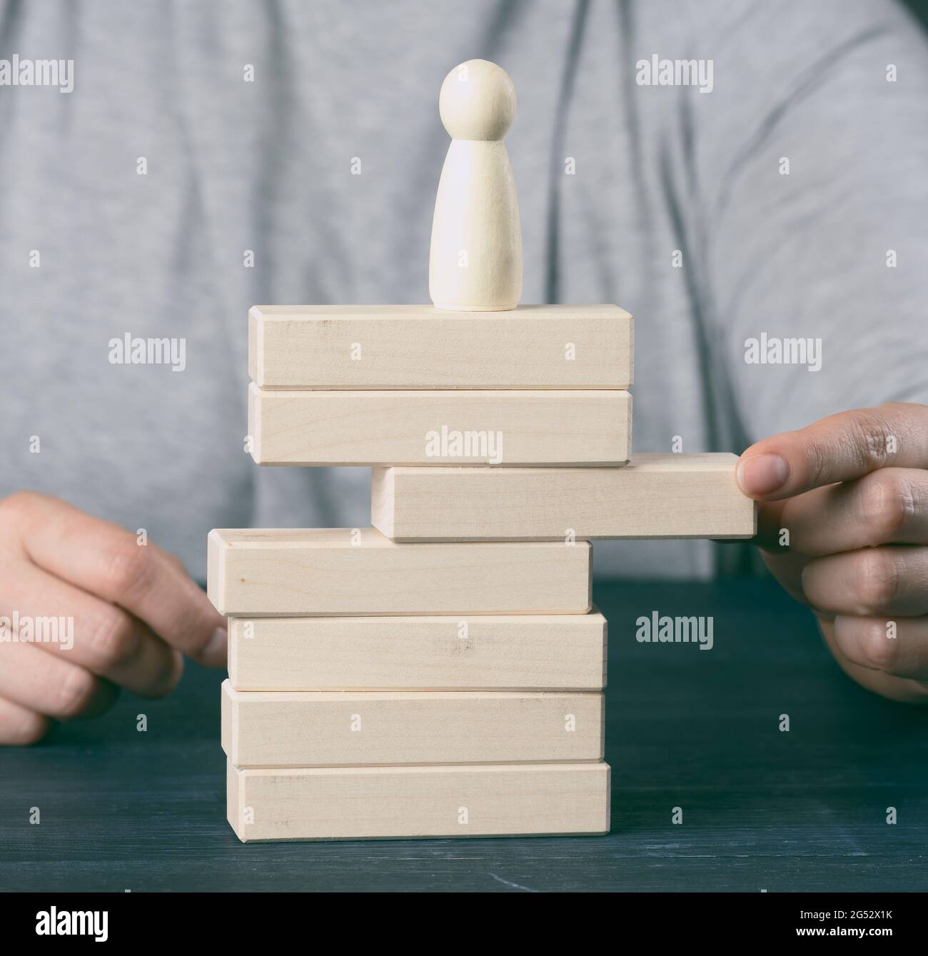 woman's hand pulls out a wooden block from the tower on which the ...