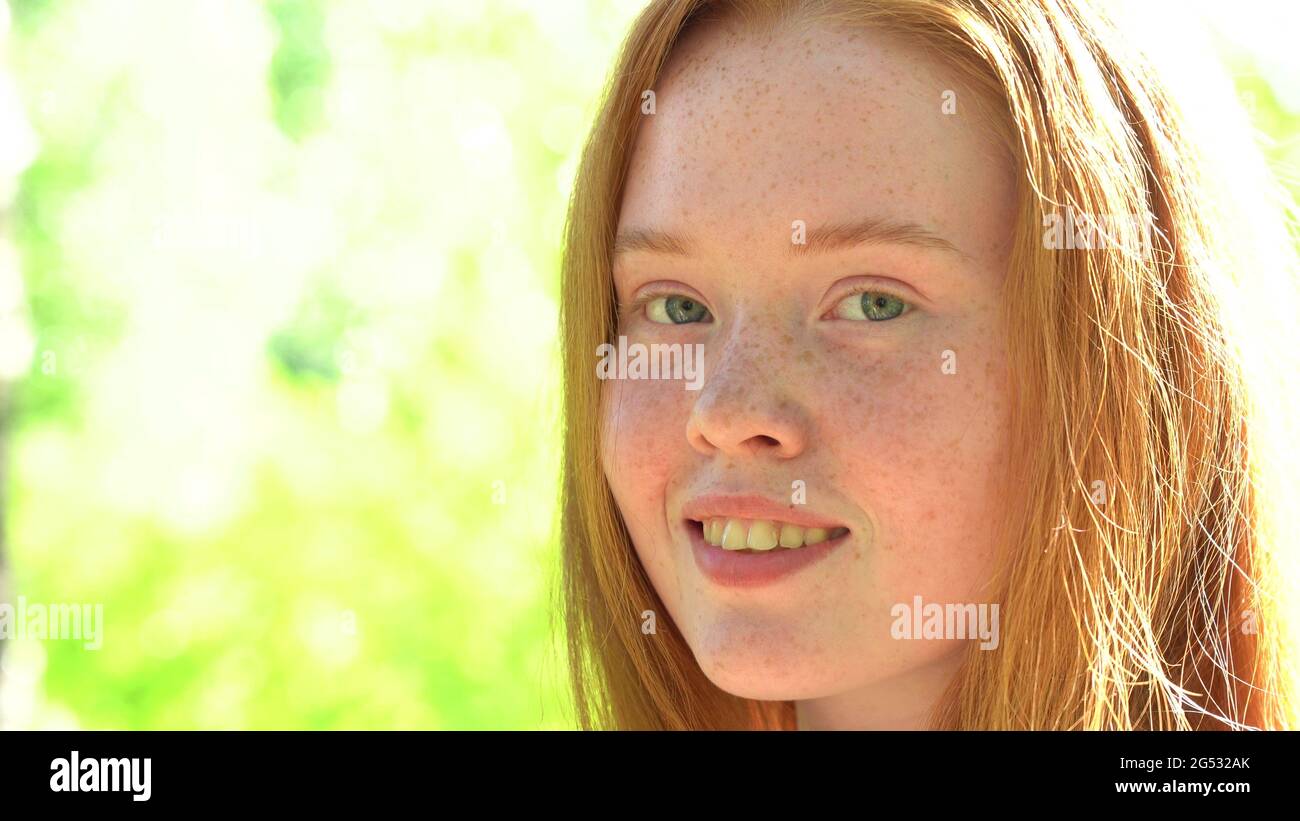 Portrait a smiling young woman with red hair and freckles against the ...