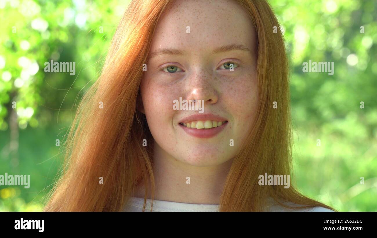 Portrait a smiling young woman with red hair and freckles against the ...