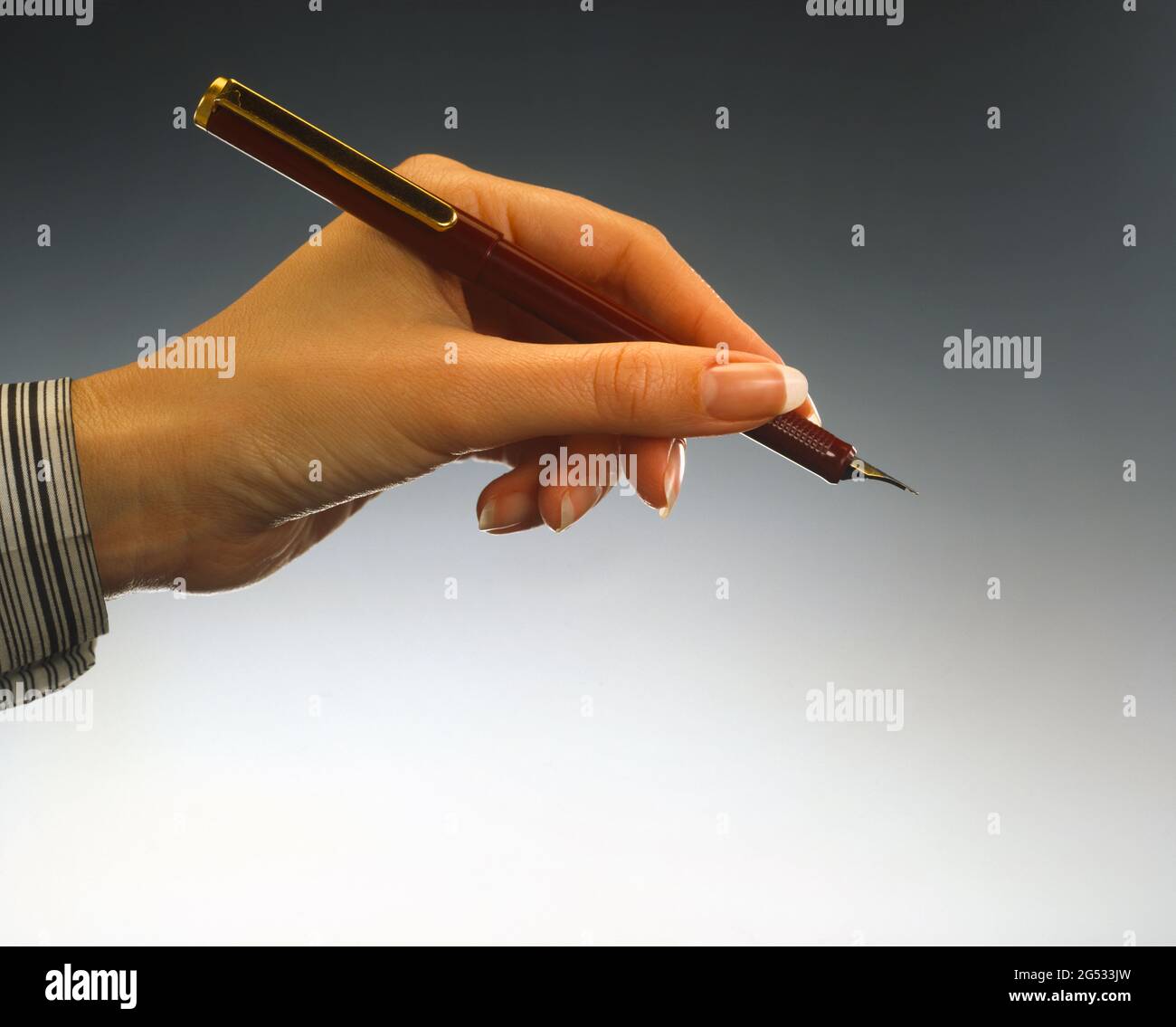 White/Caucasian female holding a fountain pen on graduated grey ...