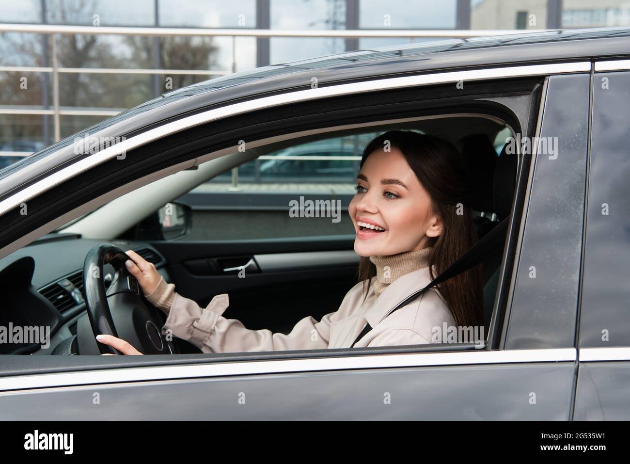 cheerful woman looking out side window while driving car in city Stock ...