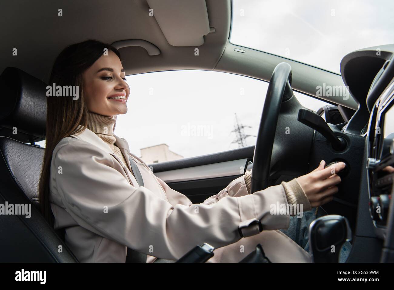 cheerful woman smiling while starting engine of car Stock Photo - Alamy