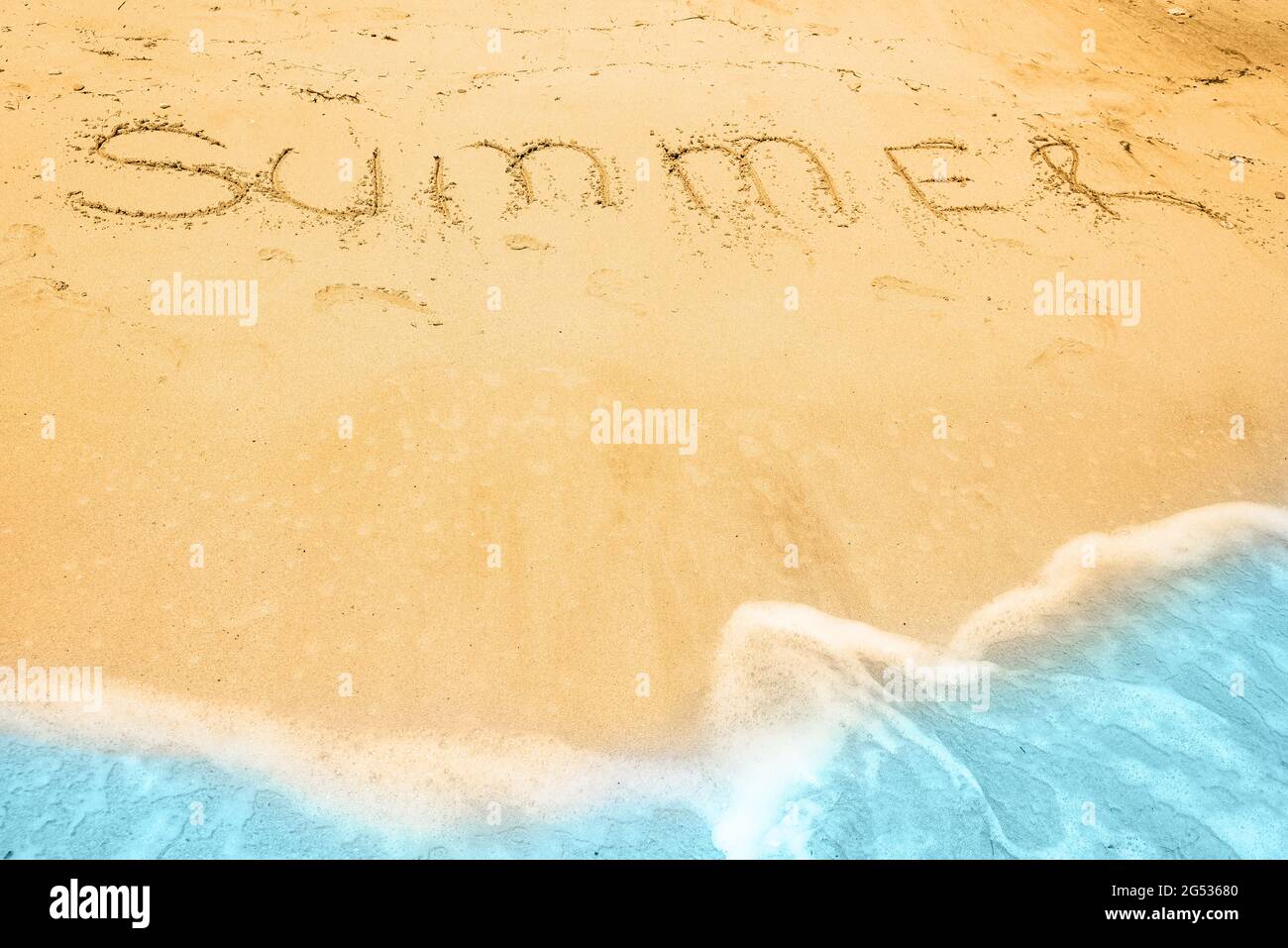 Soft wave of the sea on the sandy beach, summer word drawn in the sand ...