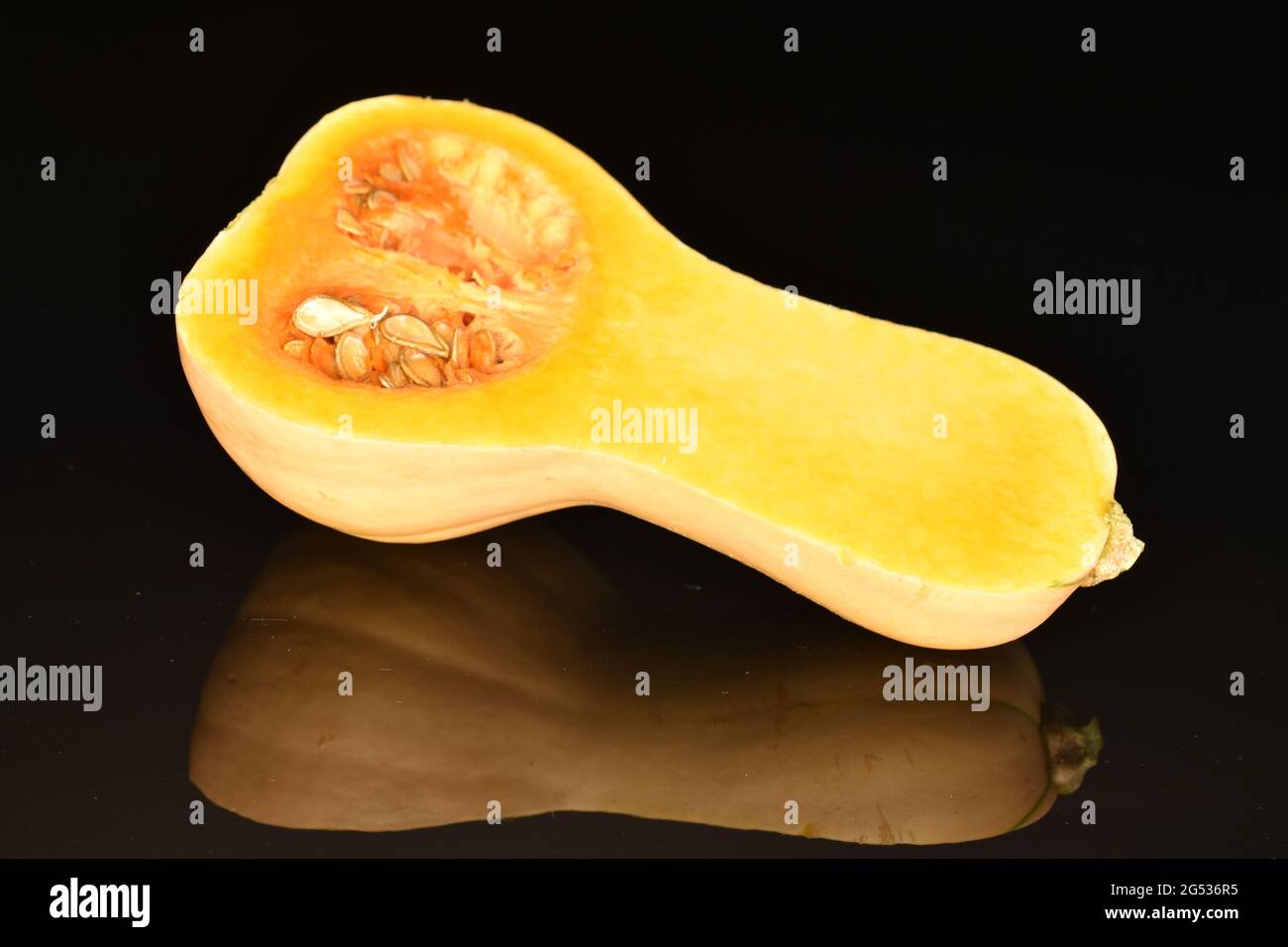 One half of ripe light yellow pumpkin, close-up, on a black background ...