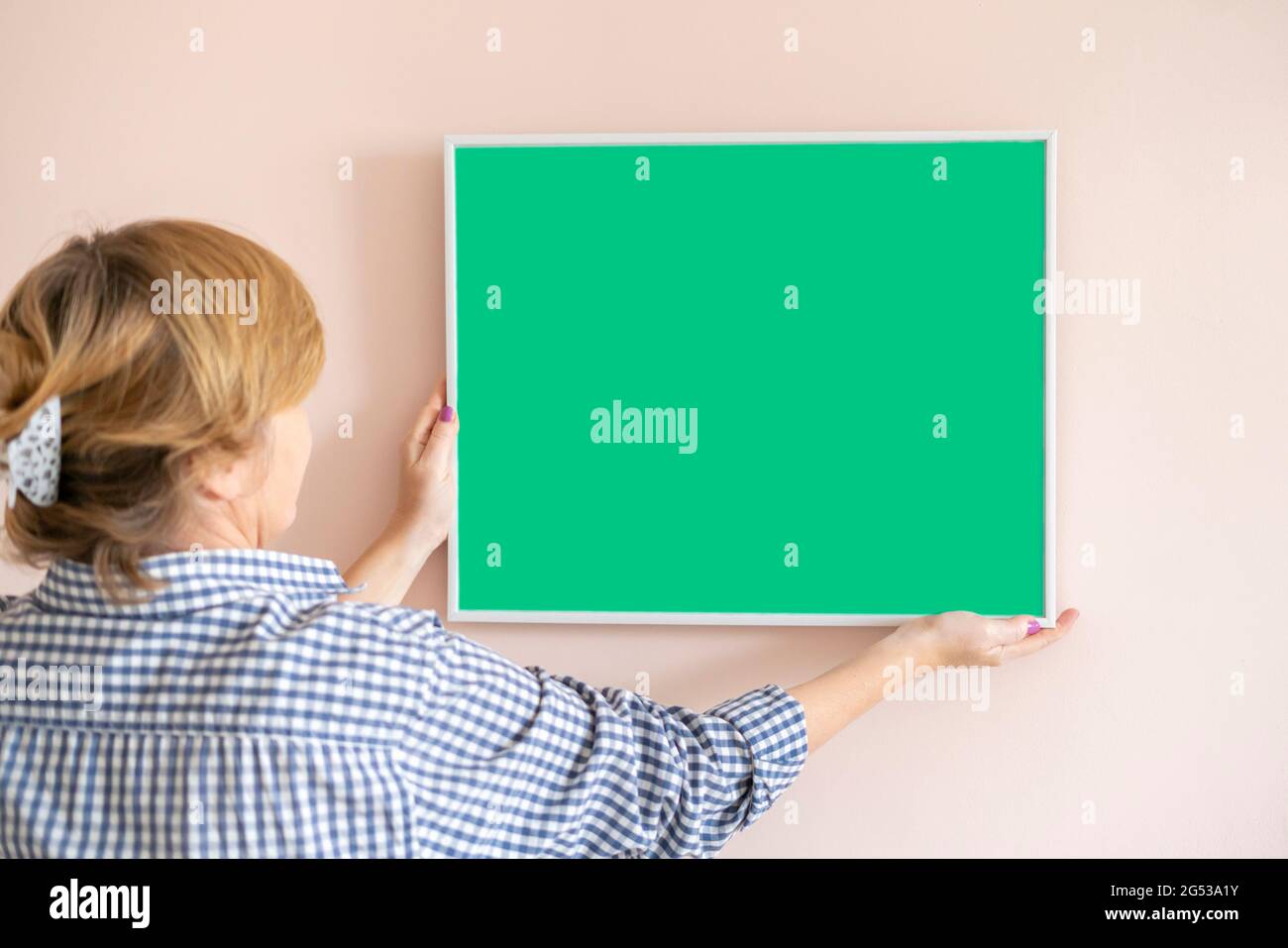 person put the empty frame for family photo on the wall at home in the ...