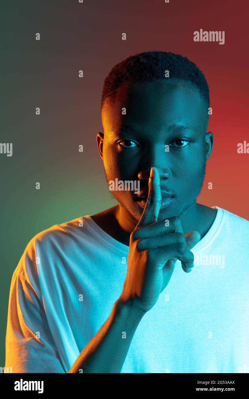 African young man's portrait on bright studio background in neon light ...