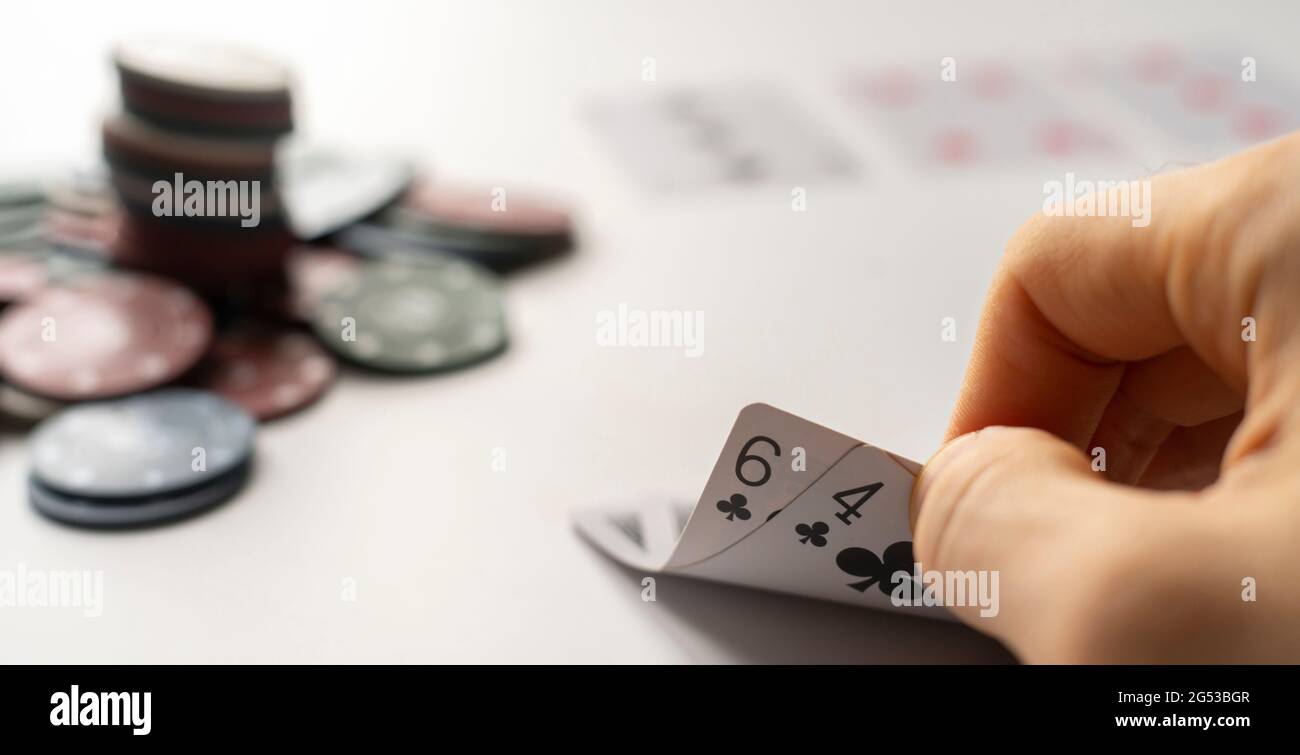 close up poker player holding a playing card on the table, win or loose ...