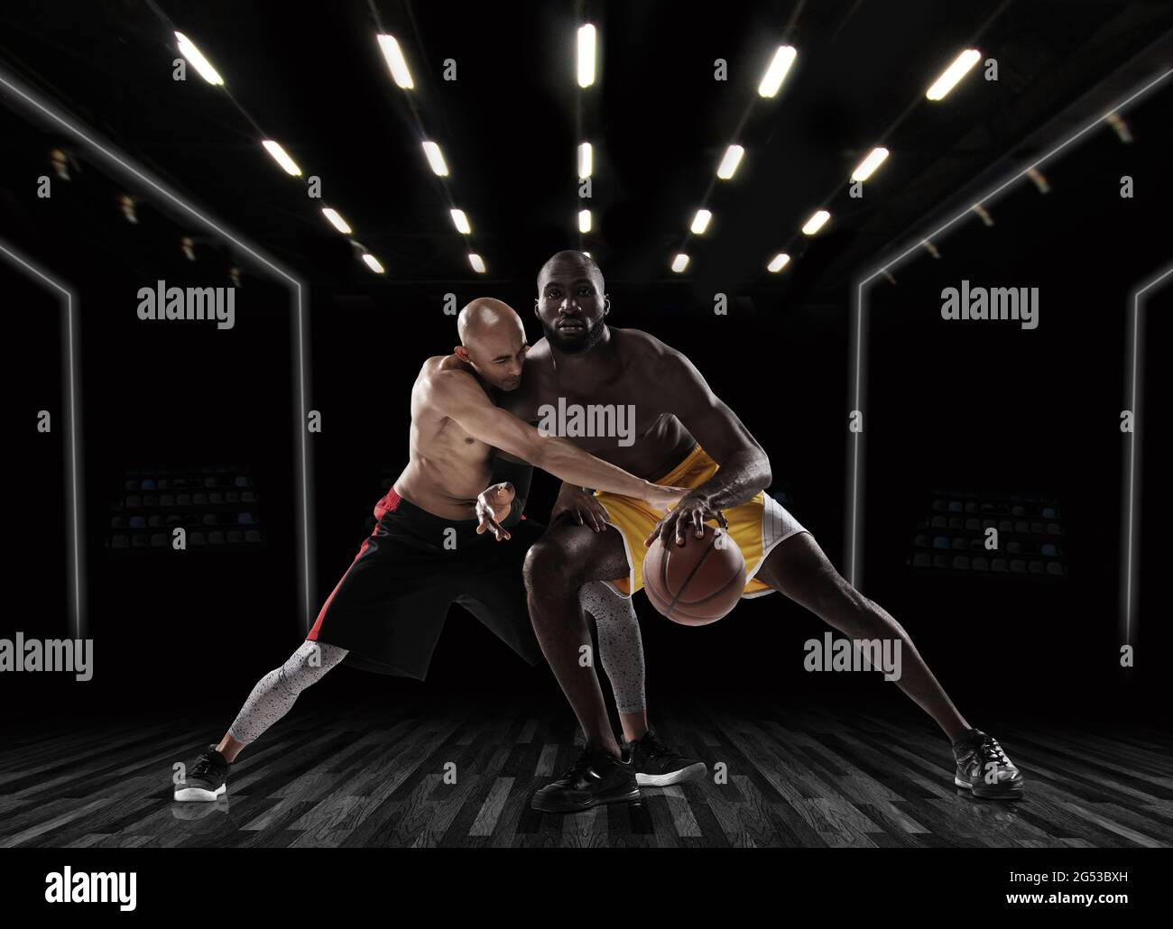 Two young sportsmen basketball players playing basketball in gym ...