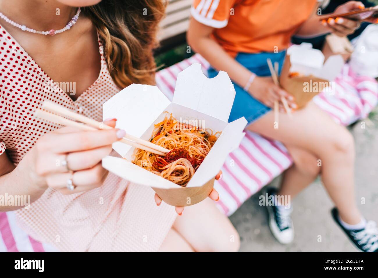 Friends eating street food outdoor on the park, enjoying summer weather ...