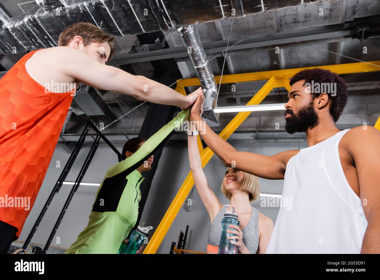 low angle view of multicultural sports people giving high five in gym ...