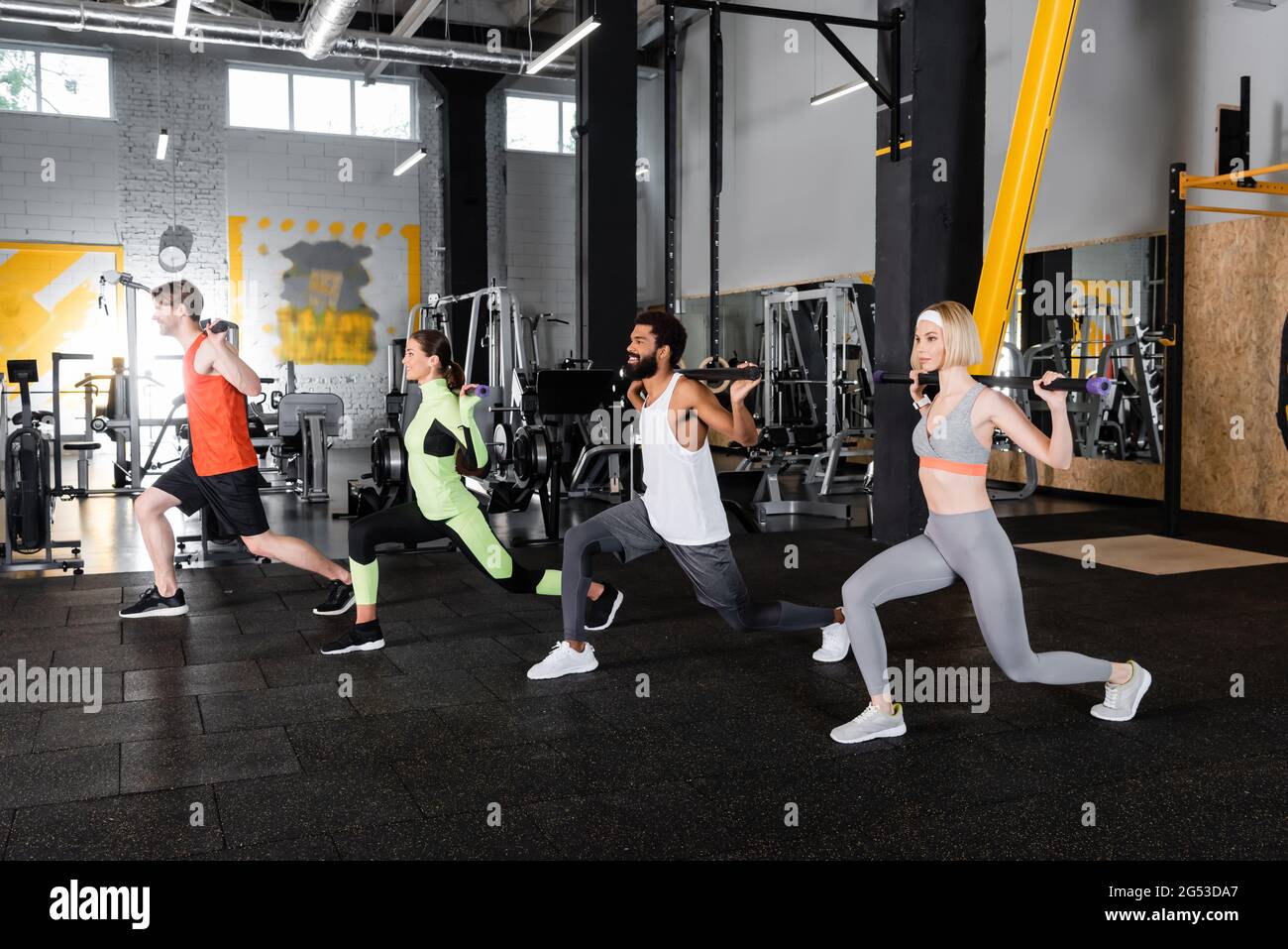 young multiethnic sports people doing forward lunges with gymnastic ...