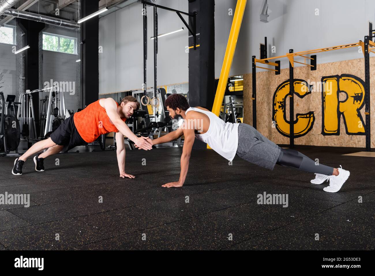 young sportsman and african american trainer shaking hands while ...