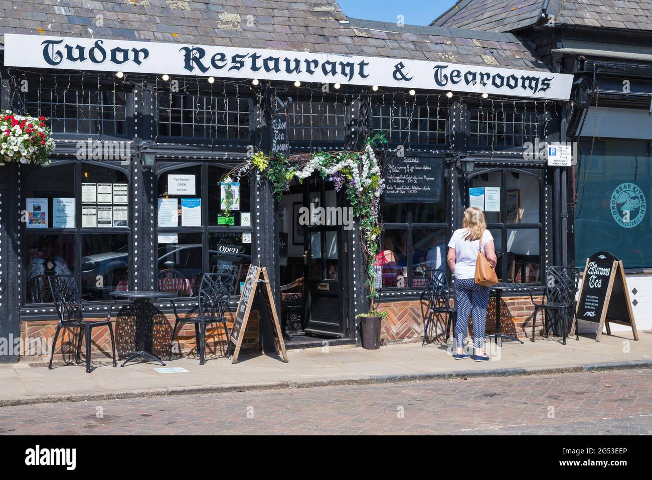 Casually dressed blonde lady checks out the menu in the window of the ...