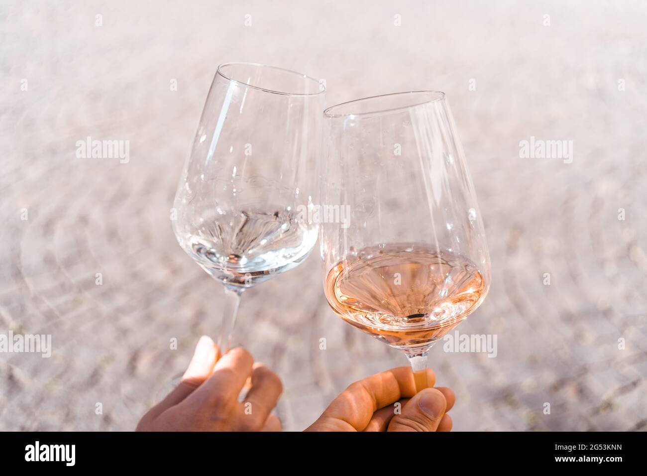 Two people toasting each other outdoors with two glasses of wine, rose ...