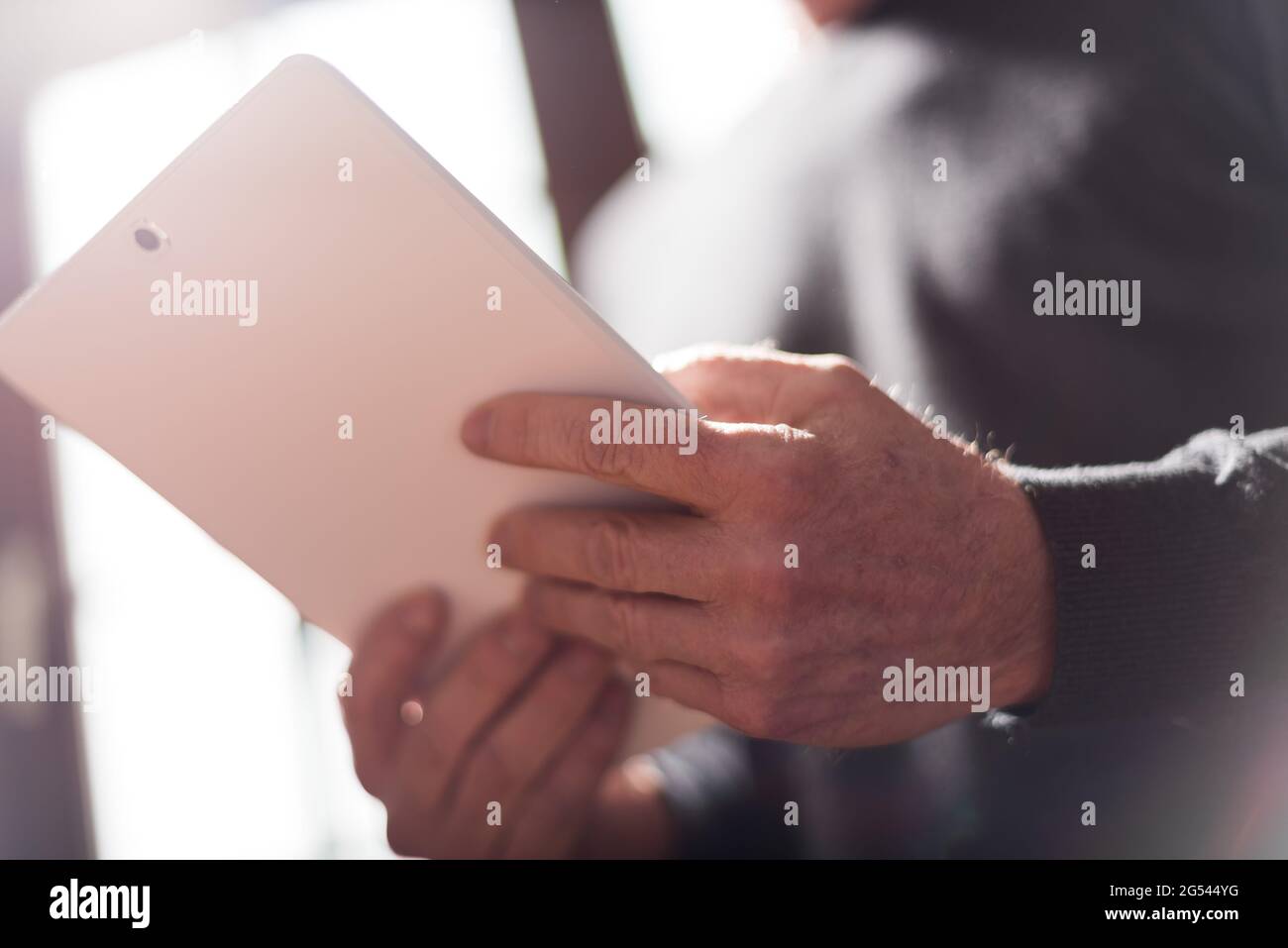 Man using his tablet at home, hard light and flare effect Stock Photo ...