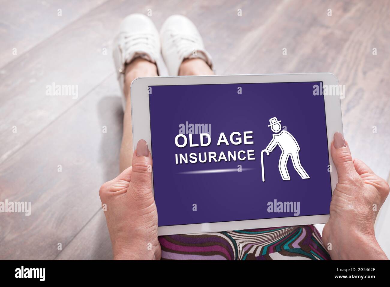 Woman sitting on the floor with a tablet showing old age insurance ...