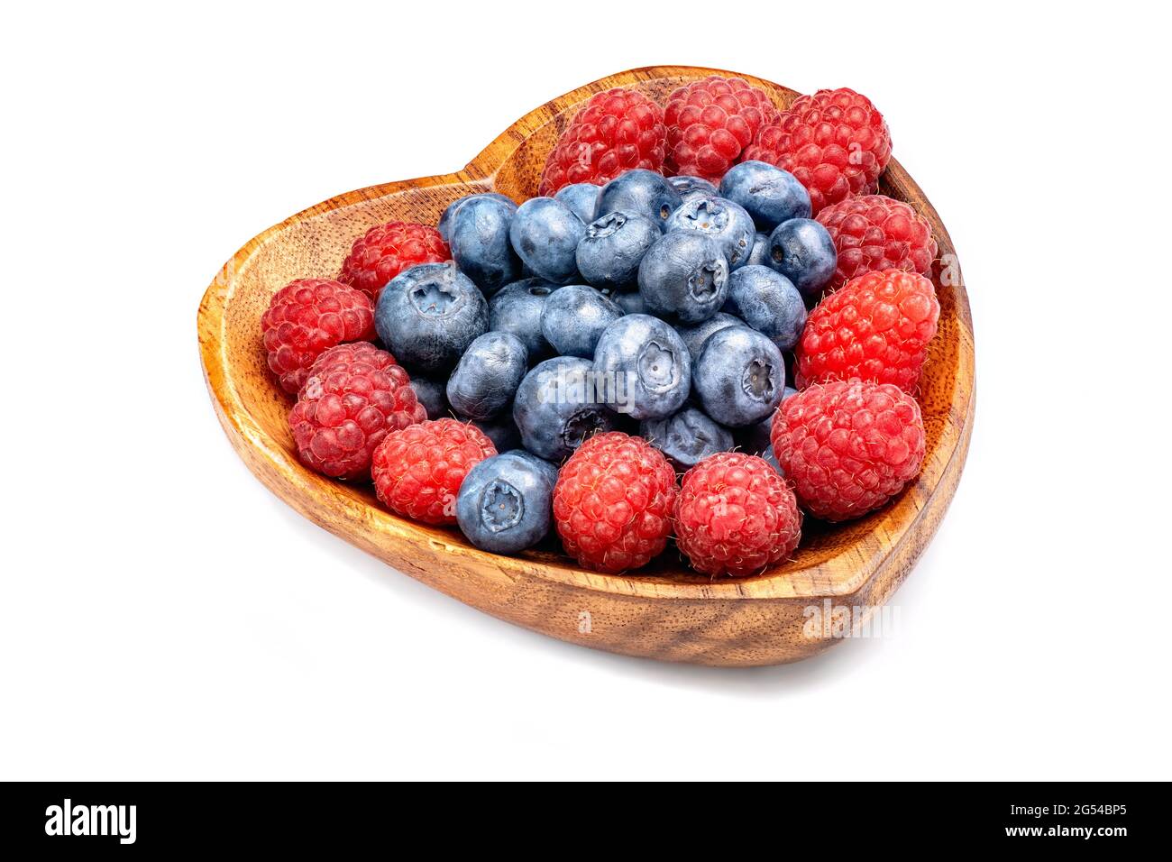 Raspberry and blueberry in wooden bowl in the shape of heart isolated ...