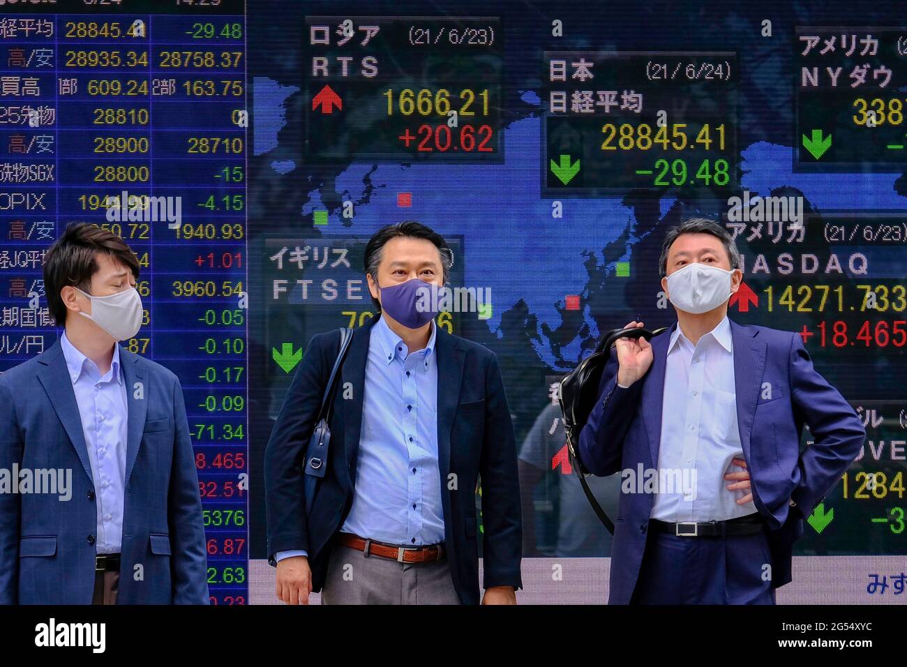 people-wearing-masks-stand-in-front-of-a-stock-price-board-showing-year