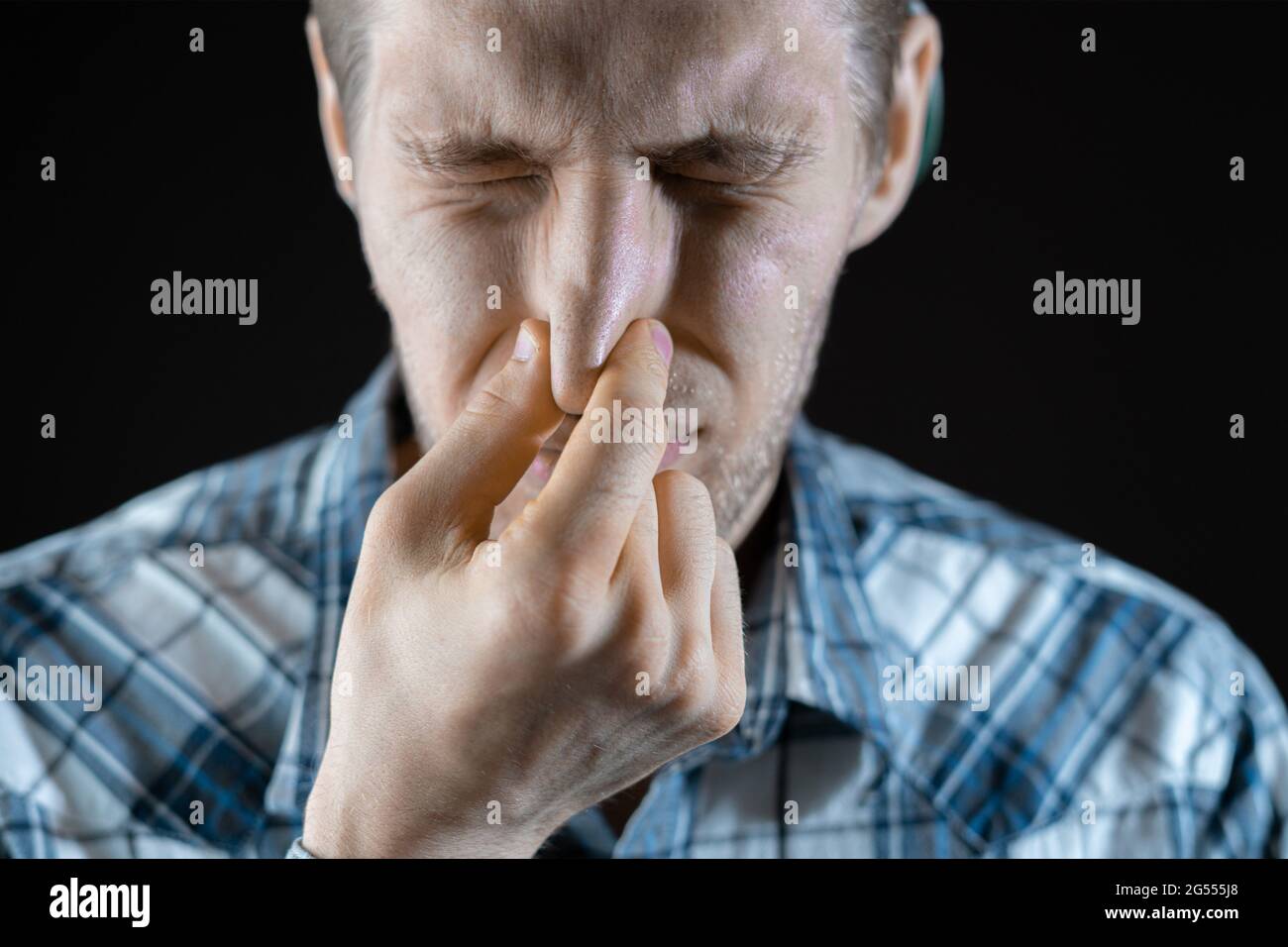 man close his nose on dark background, stink smell, fells disgusting ...