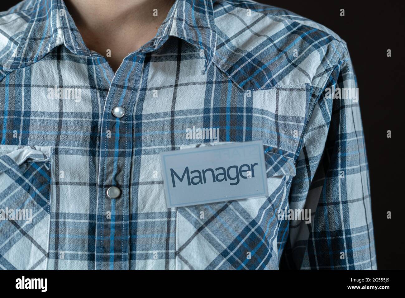 male employee holding a badge with text "manager" word on his shirt ...
