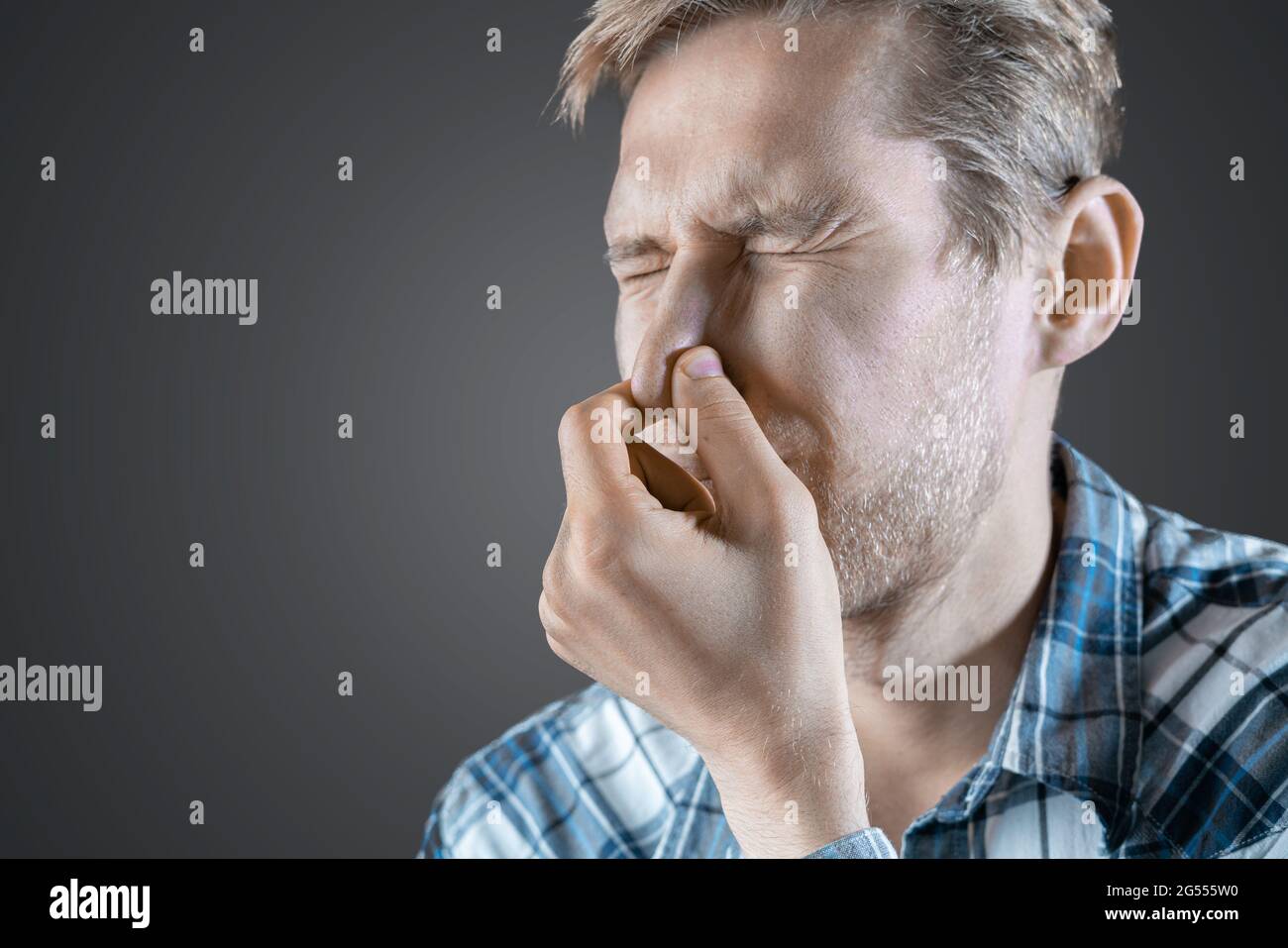 man close his nose on dark background, stink smell, fells disgusting ...