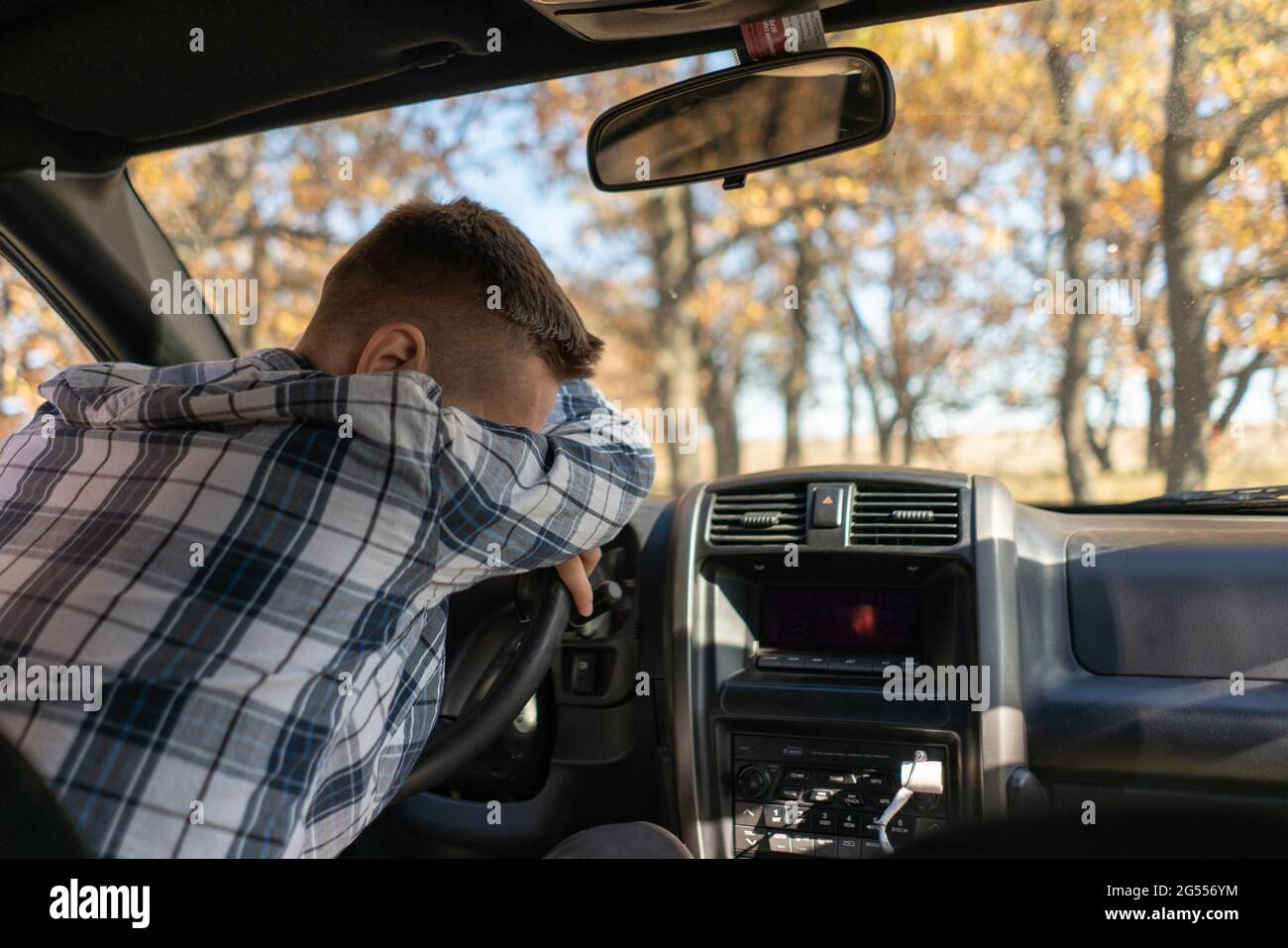 a young male sleeping in the car on the driver seat, having a rest ...