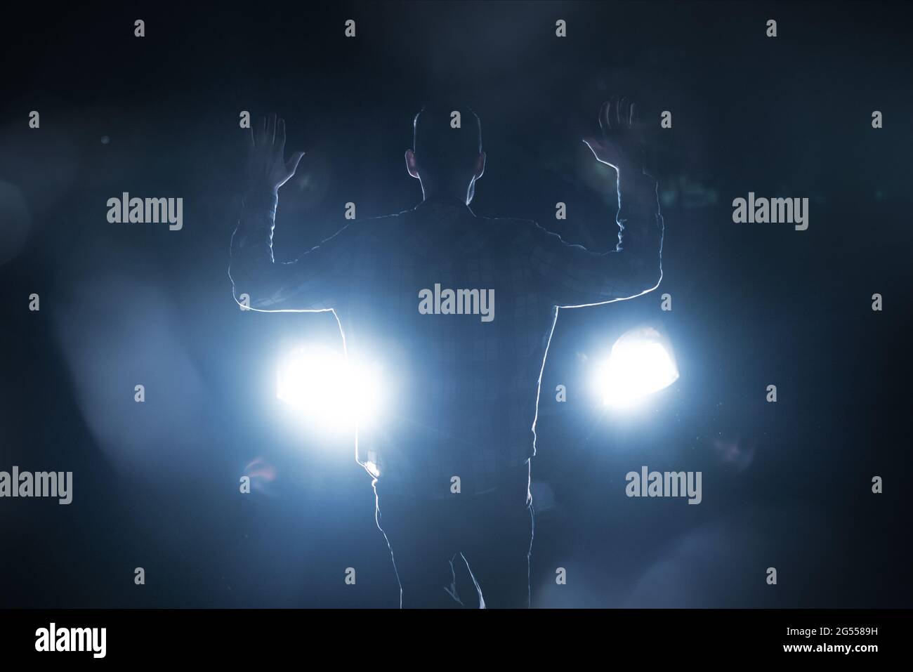 silhouette of a male criminal suspect with hands up during night ...
