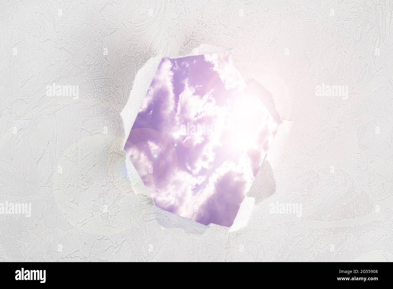 a blank piece of torn paper with a hole in it and the cloudy sky behing ...