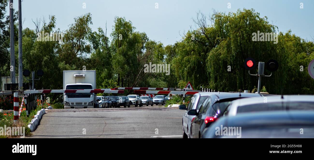 Cars stand in front of gates at a railway crossing. A red traffic light ...