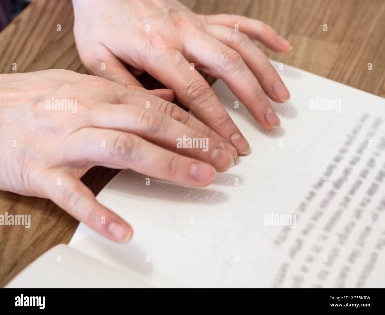 female fingers read book with braille and usual text closeup on wooded ...