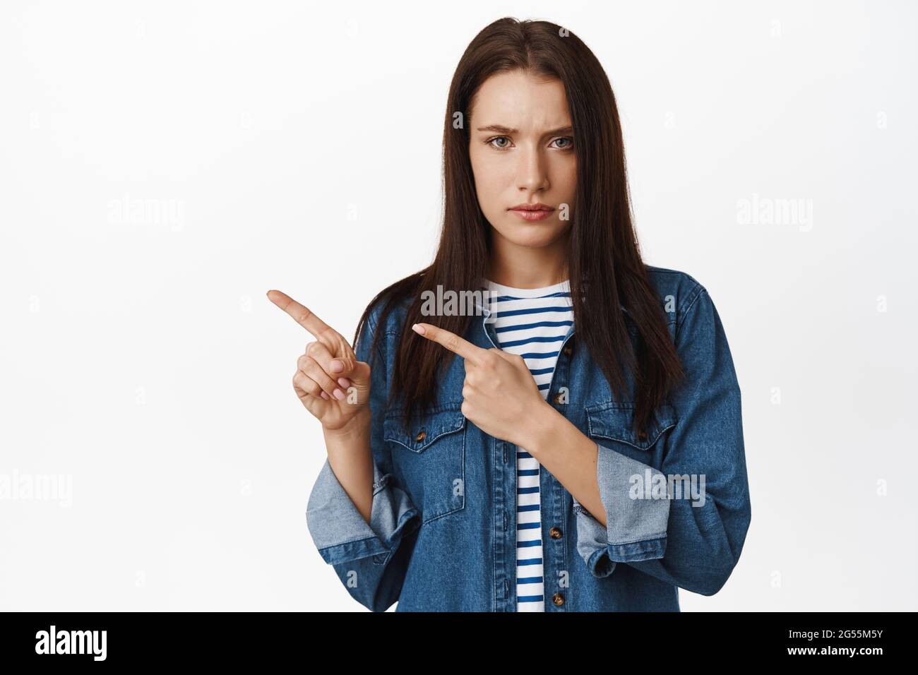Disappointed frowning woman pointing left, looking serious and ...