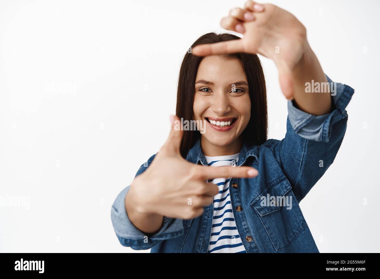 Taking picture of you. Smiling brunette adult woman looks through hand ...