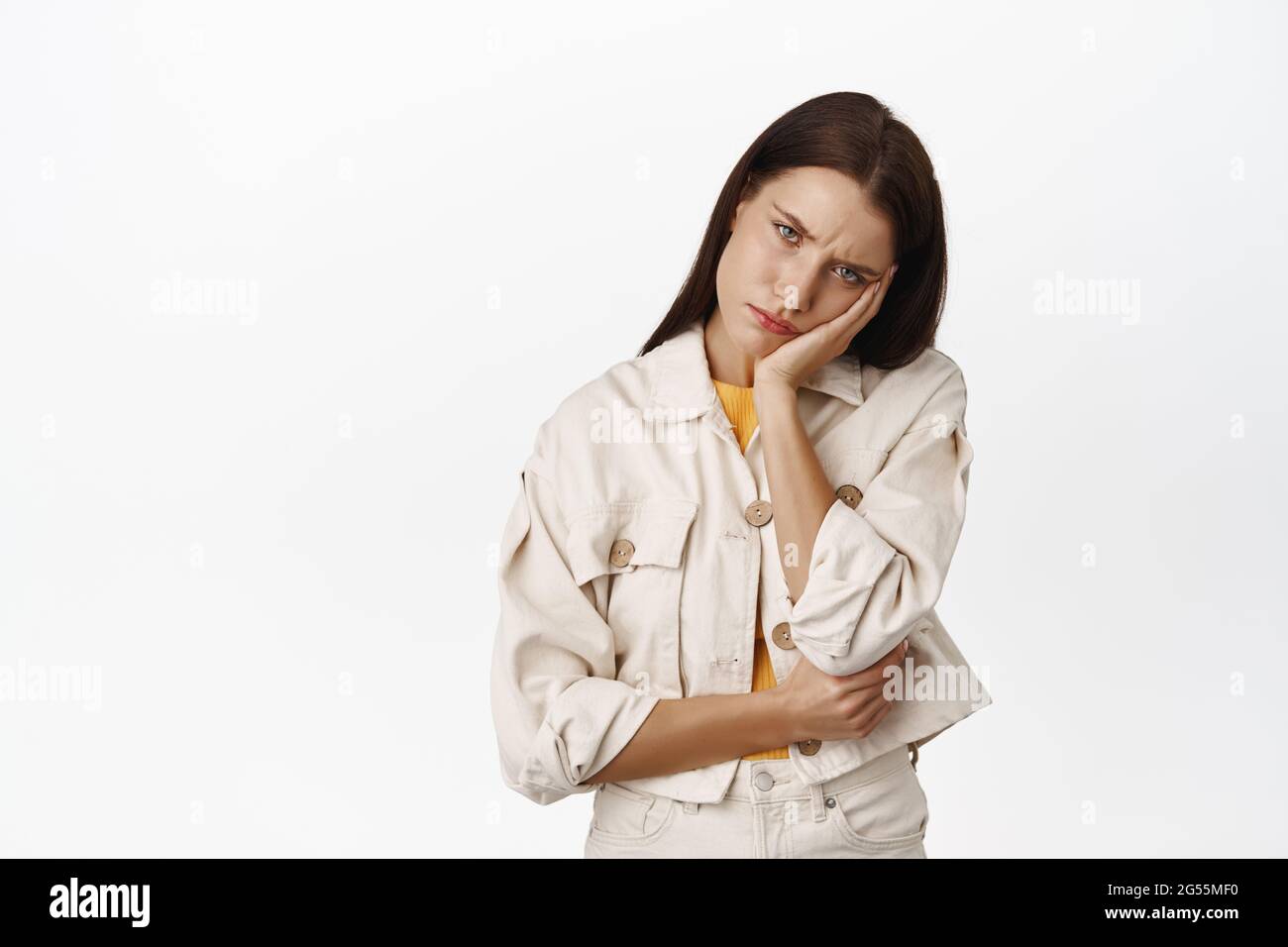 Bored and upset young woman, lean face on hand, furrow eyebrows and ...