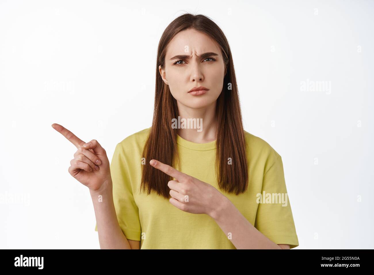 Confused young woman look clueless, pointing fingers left and frowning ...