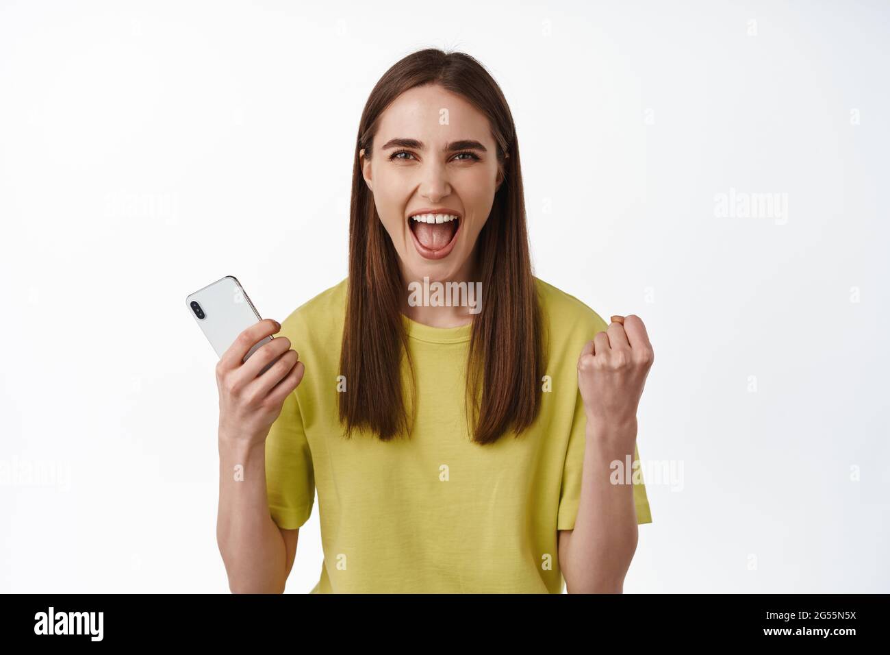 Girl winning on mobile phone. Happy woman celebrating success, holding ...