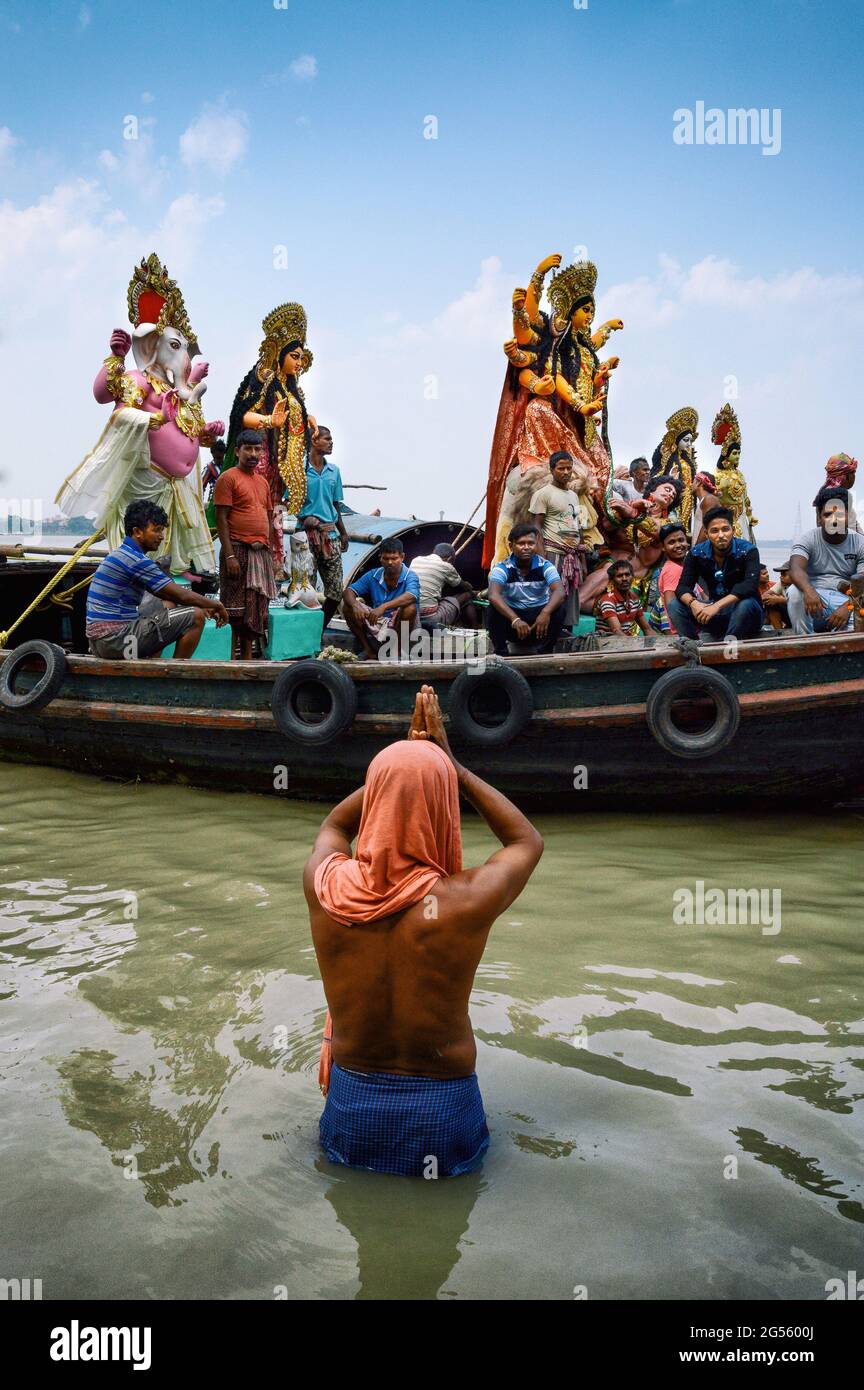 A man prays to an idol of Goddess Durga while being transported by boat ...