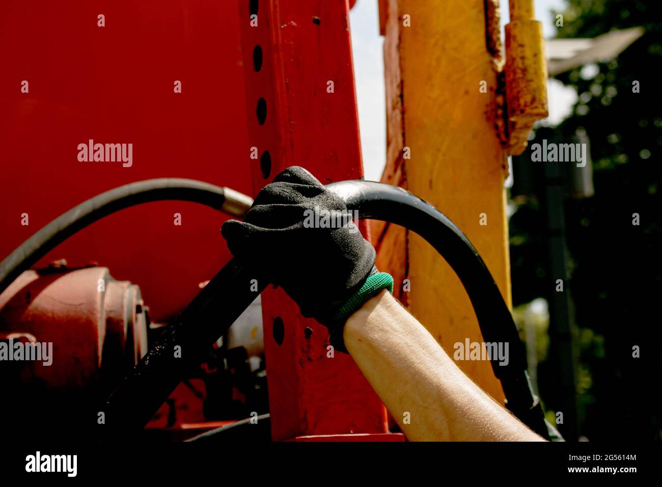 A woman's hand in a rubber glove holds a watering hose. The hose must ...