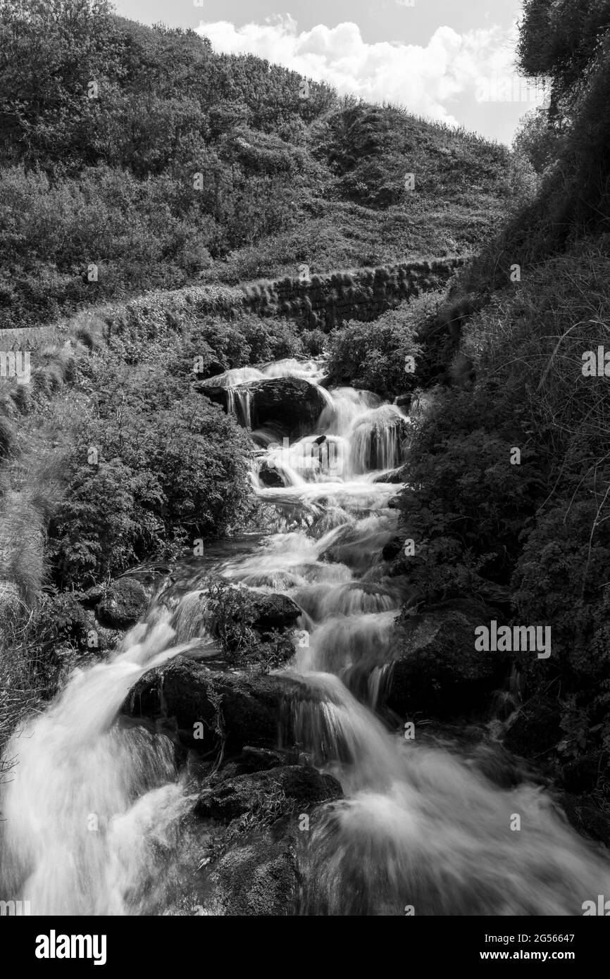 Long exposure of a waterfall flowing onto Lee Abbey Beach in Devon ...