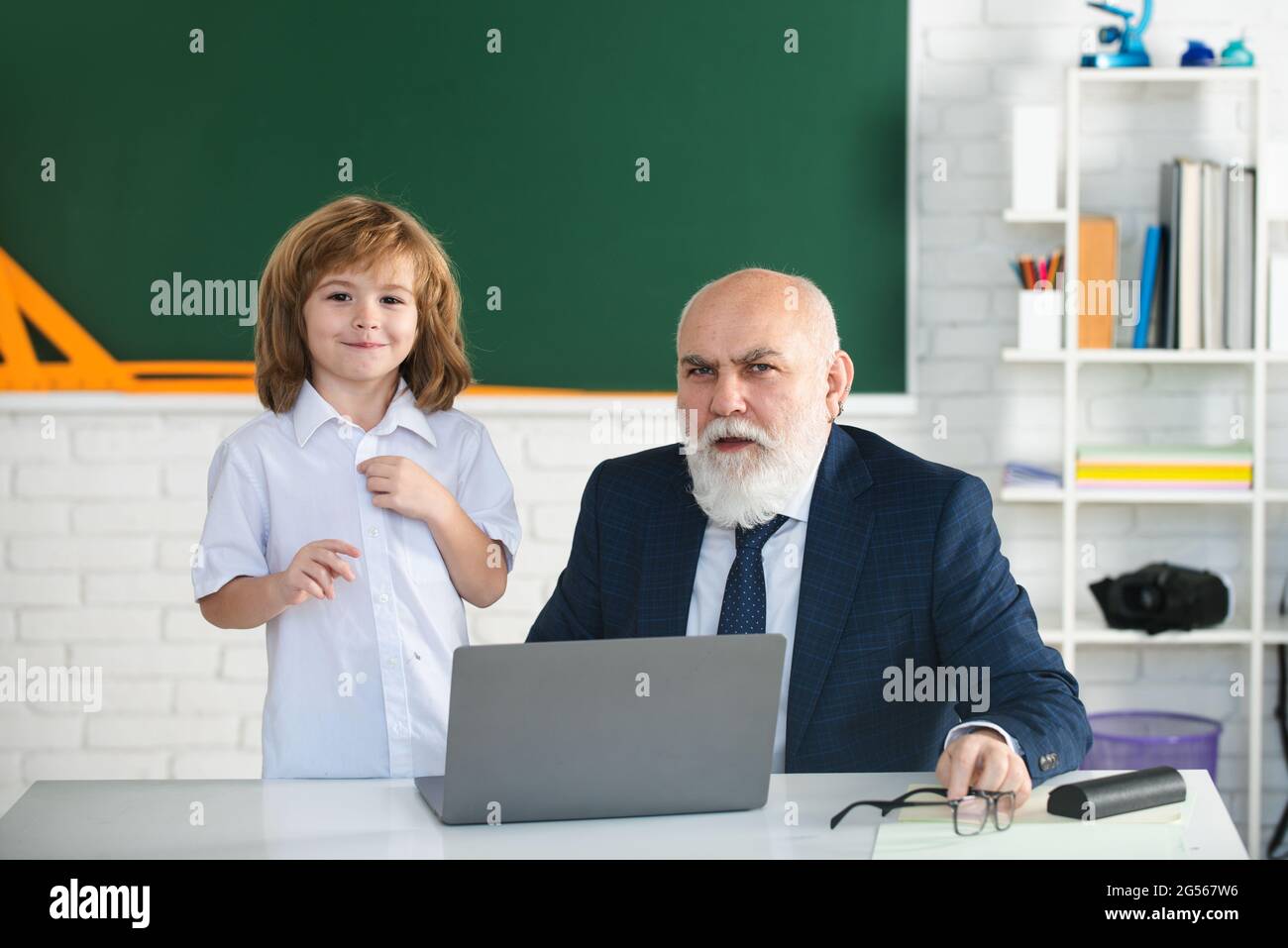 Teacher with schoolboy in classroom. Pupil with laptop. Education and ...