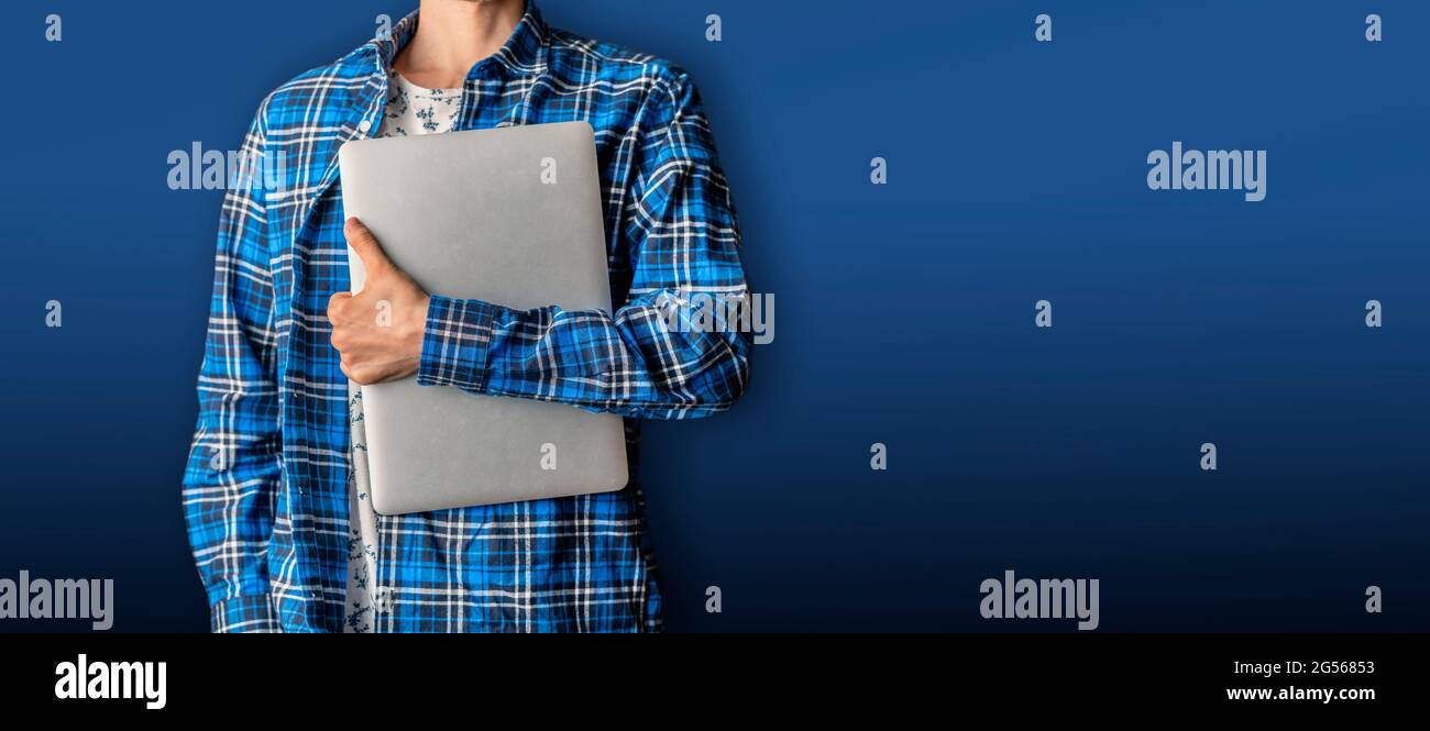 man holding and carrying the laptop, hug the cumputer standing against ...