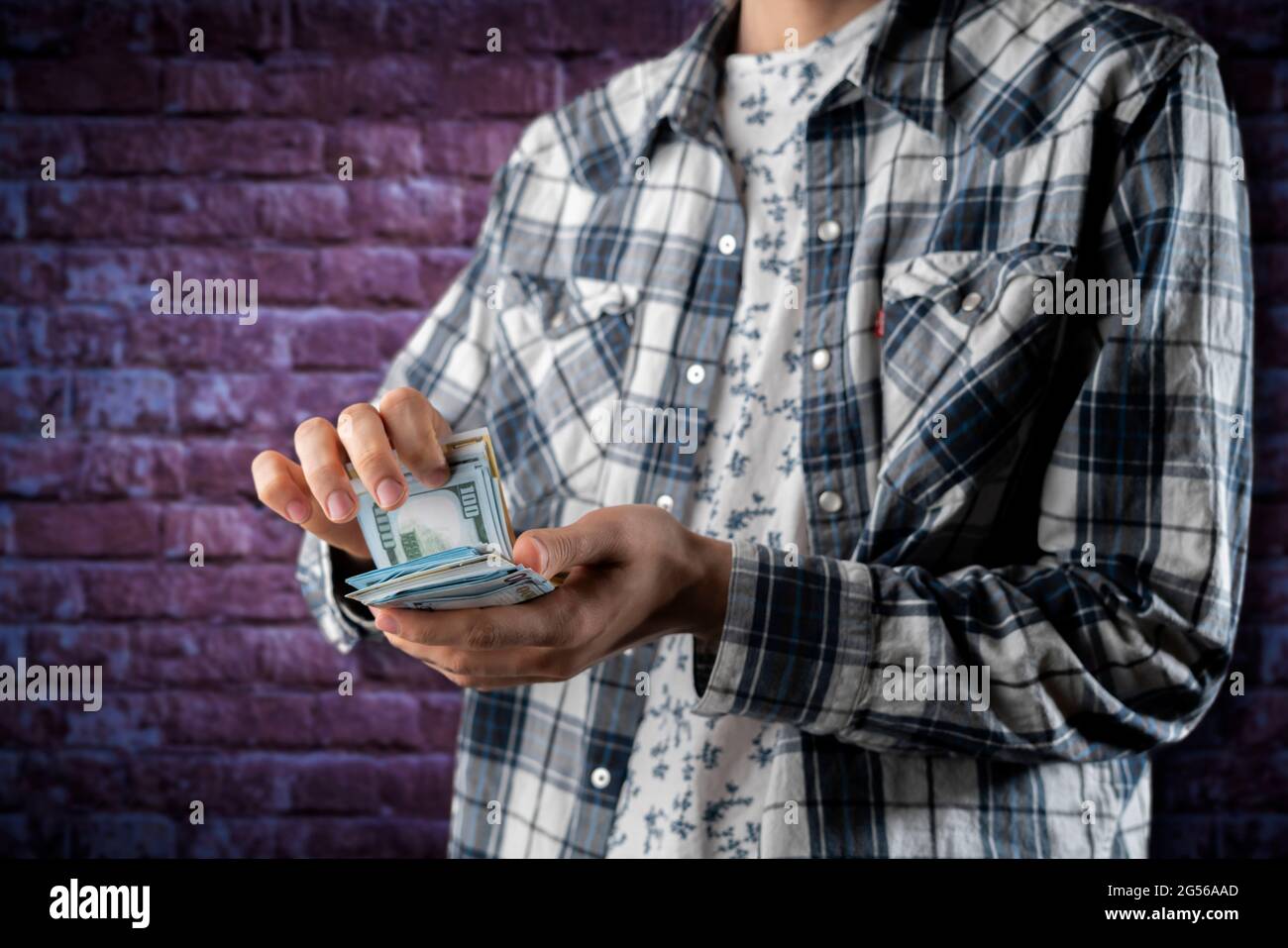 person standing against the color wall and counting the bunch of money ...