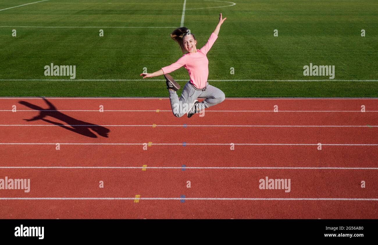 Happy energetic girl child jump on running track, athletics Stock Photo ...