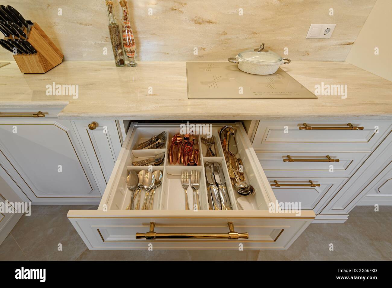 Drawer pulled out in cabinet at luxury beige and gold classic kitchen ...